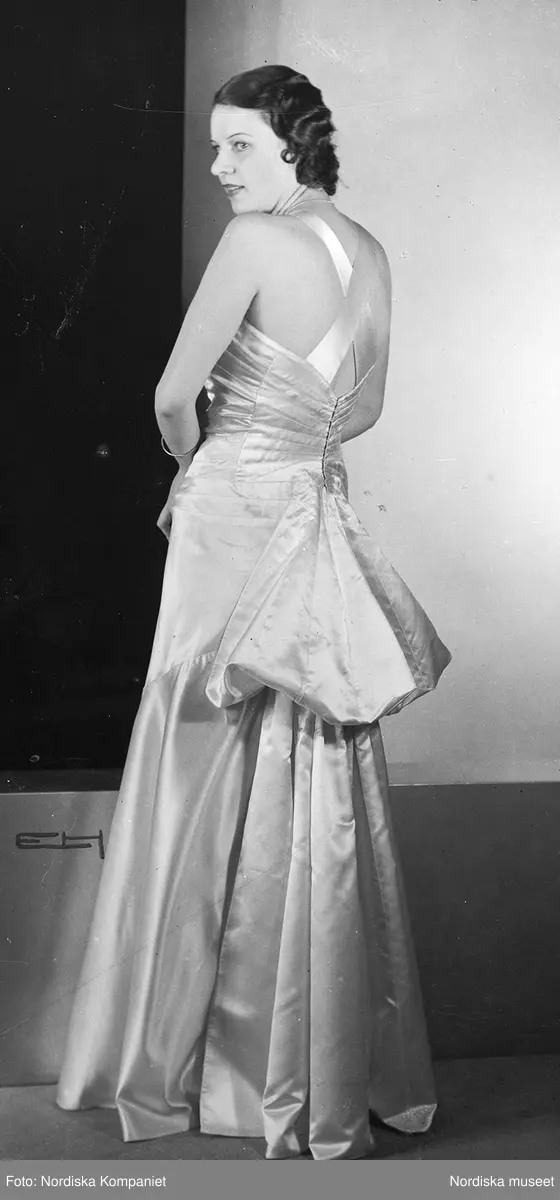 Modell i vit aftonklänning med axelband i kors i ryggen. Från Chanel ...