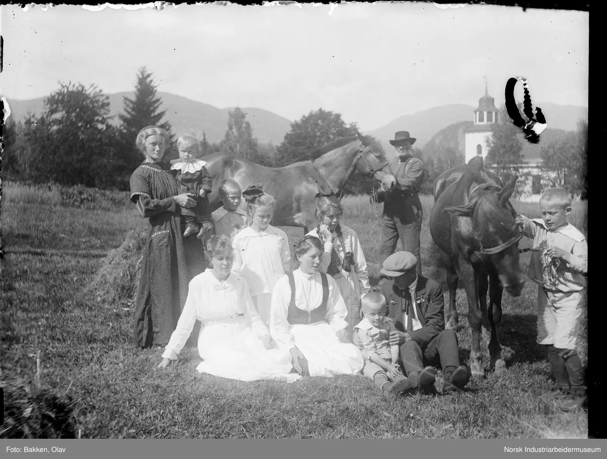 Mennesker og to hester med grime og leietau sittende og stående på ...