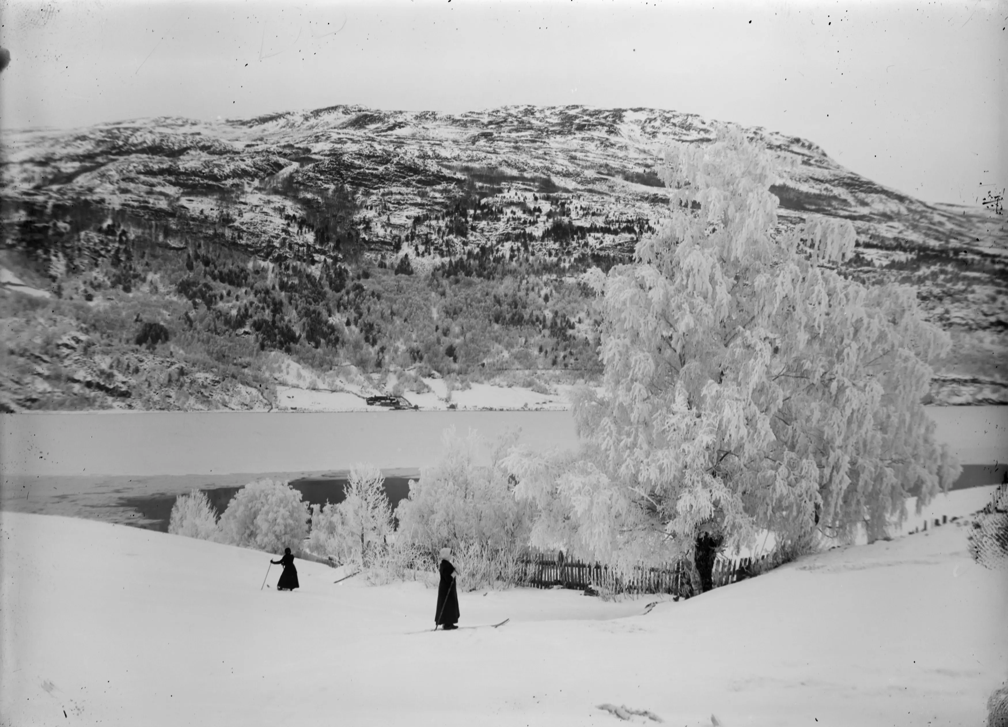 To skiløpere på Storvik (Storrvik) Nordigard, Tessand. Vågåvatn med ...