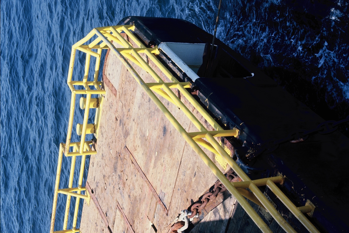 Dekket på et skip sett ovenfra. Det går en vaier og en tykk ...