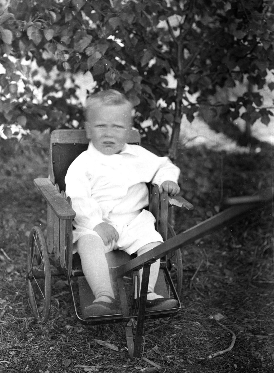 Barn i stol ute i hagen. - Bø Museum / DigitaltMuseum