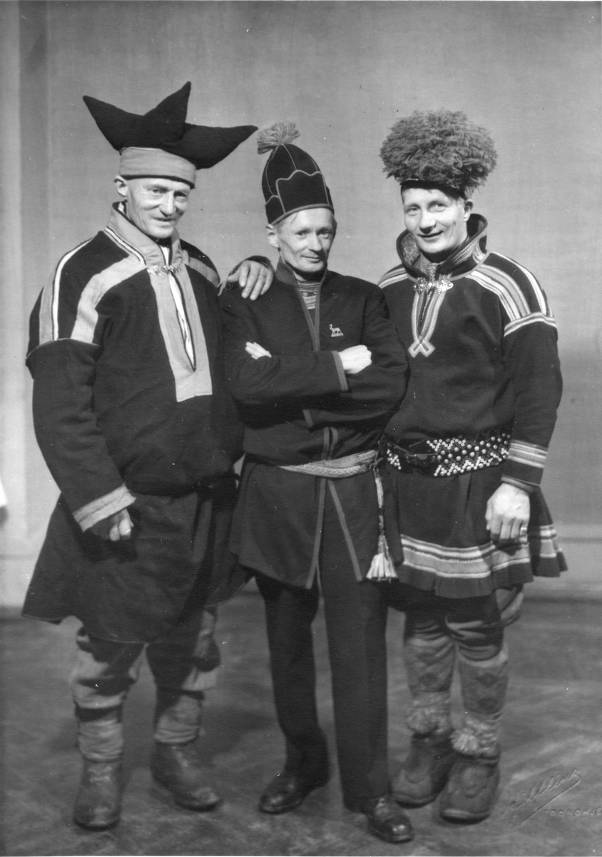 Tre menn i samiske kofter portrettert i atelier. Koftene er henholdsvis ...