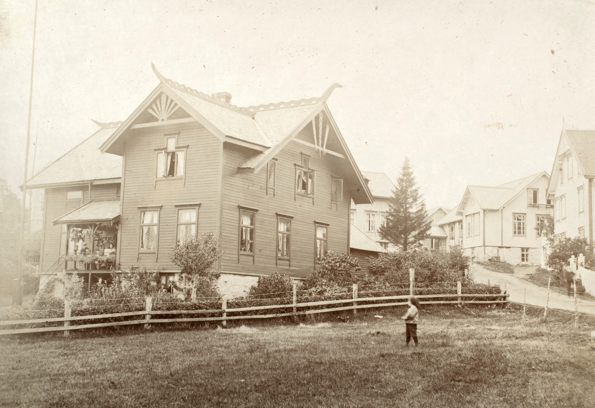 Prospektfotografi av et hus i dragestil i et boligområde. En gutt står ...