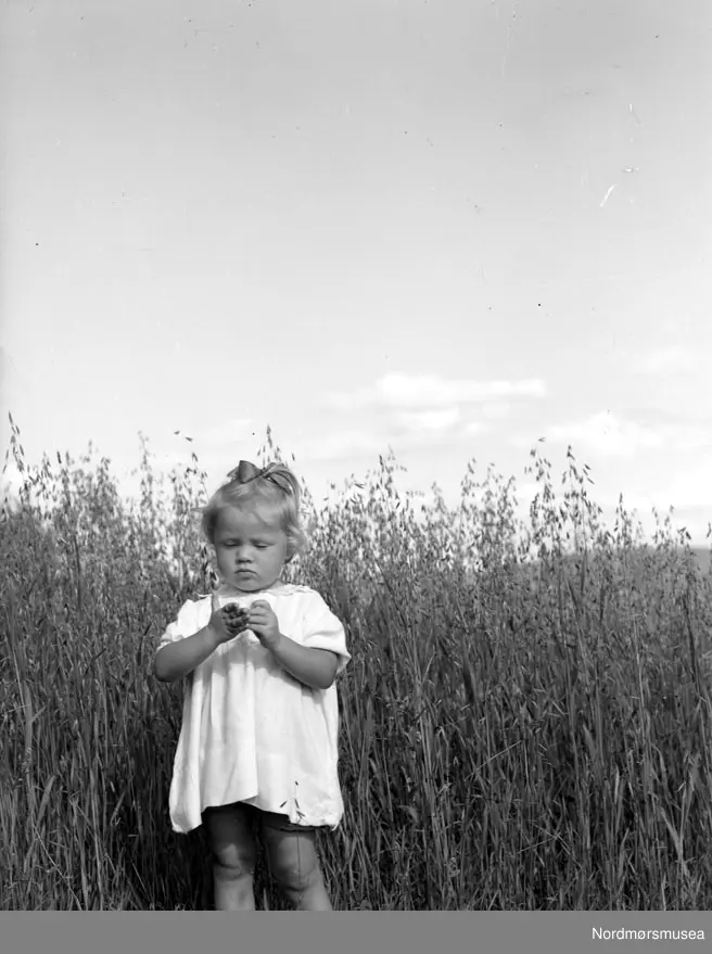 Her ser vi en kvinne sammen med en pike ved en boligport. Trolig enten ...